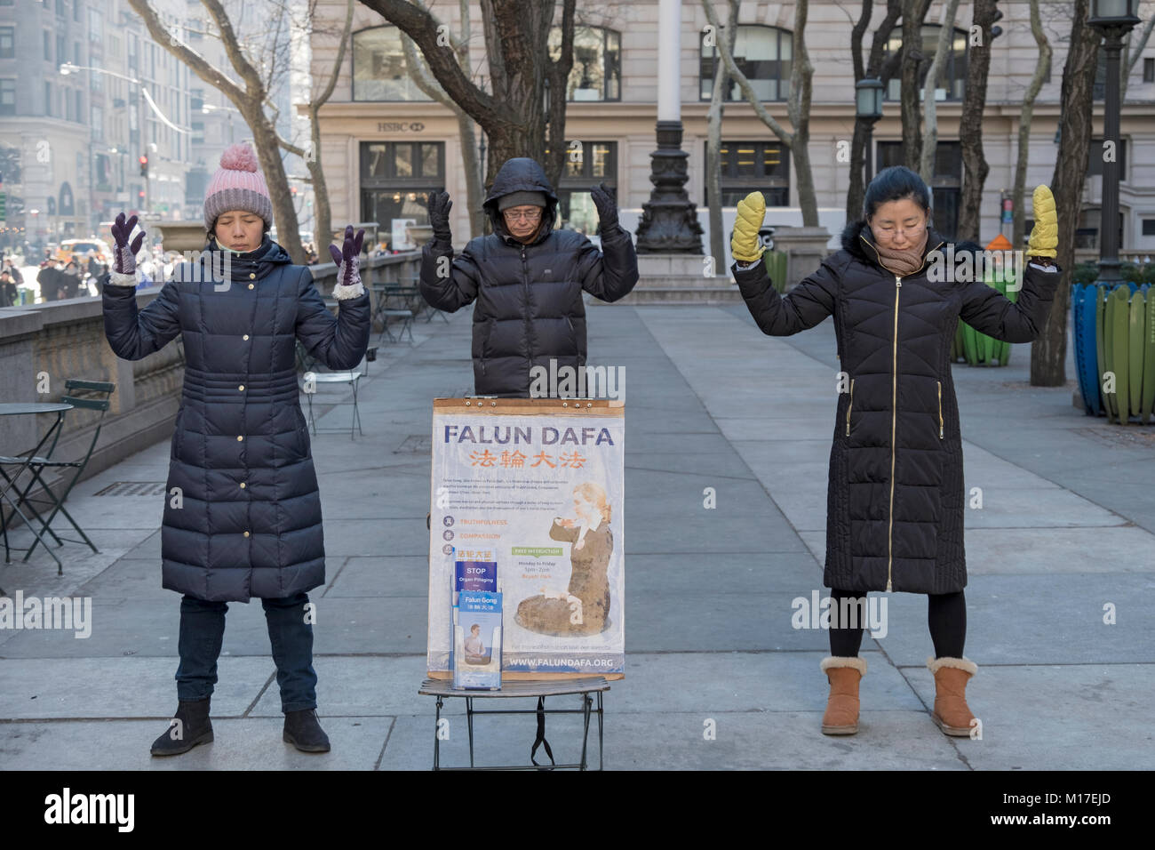Three adults doing Falun Dafa exercises at the main branch of the New ...