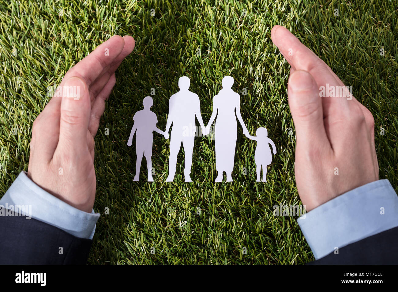 Elevated View Of A Person's Hand Protecting Family Paper Cut Out On ...