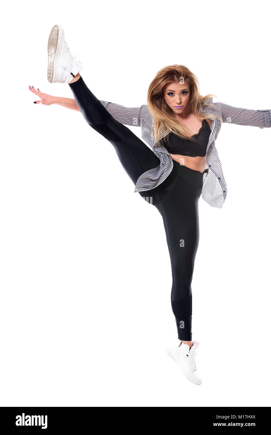 Energetic woman dance hall dancer jumping with raised leg in mid air ...