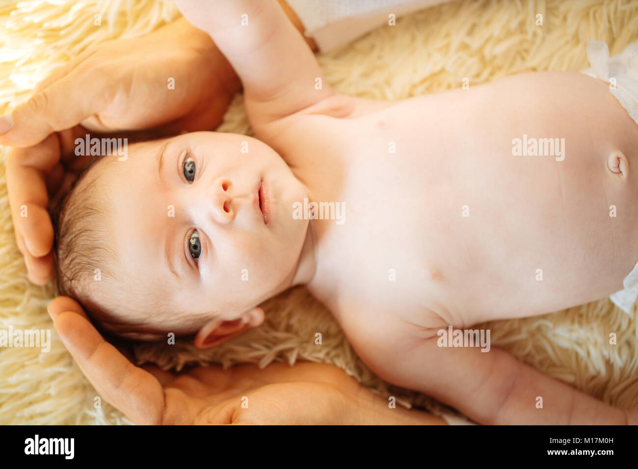 newborn baby lying down smiling looking at camera while father holding his head Stock Photo - Alamy