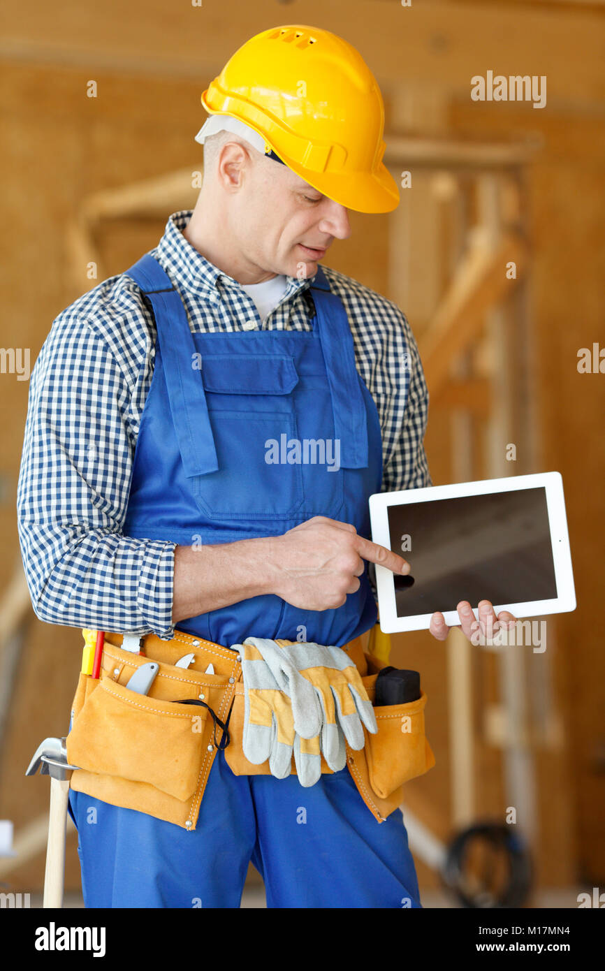 Construction worker pointing at digital tablet at construction site ...
