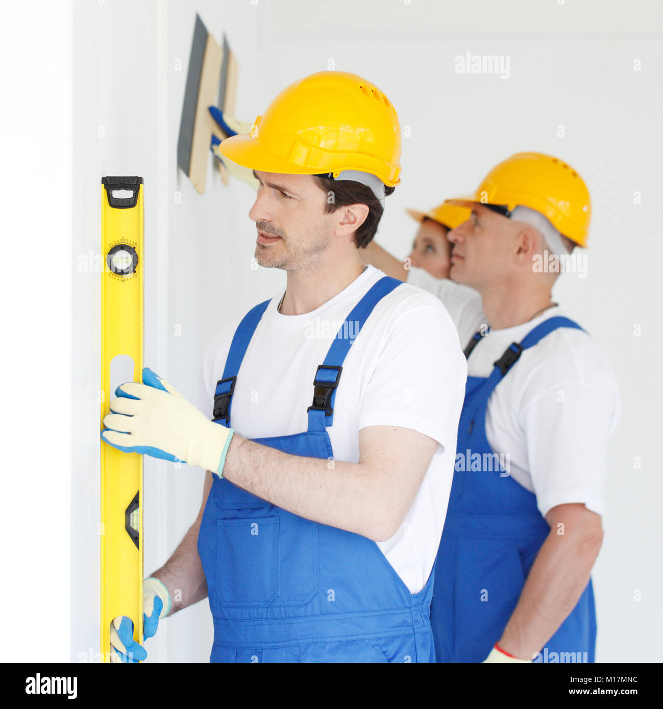 Team of workmen align wall using tools Stock Photo - Alamy