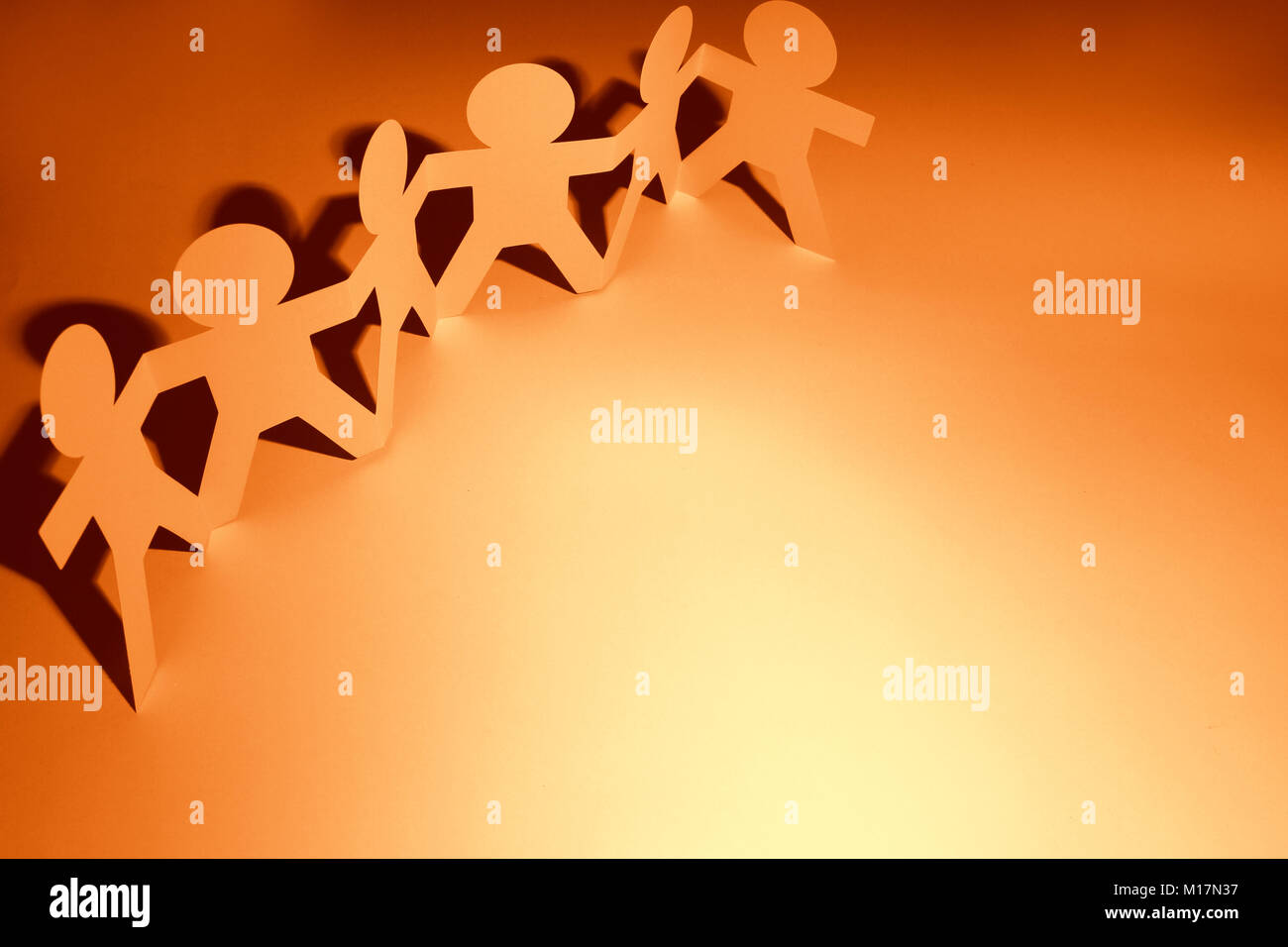 Team of paper chain people in a row holding hands. Copy space Stock ...