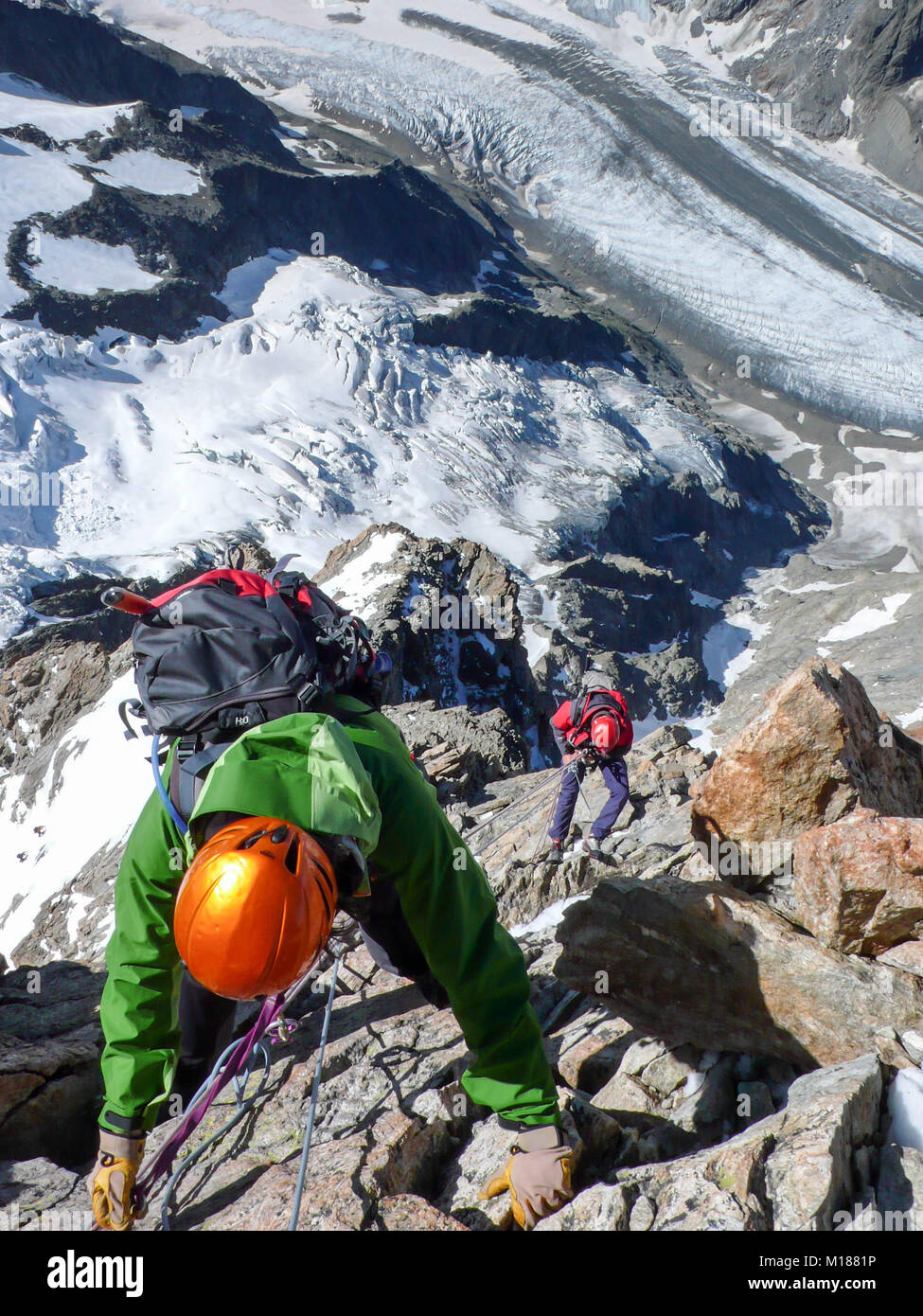 mountain guide and client abseiling from a high alpine peak near ...