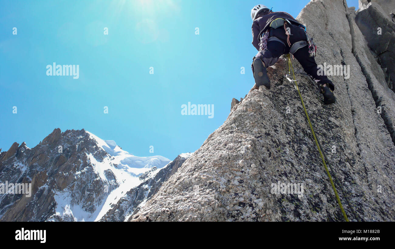 male rock climber on a steep granite route in the mountains near ...