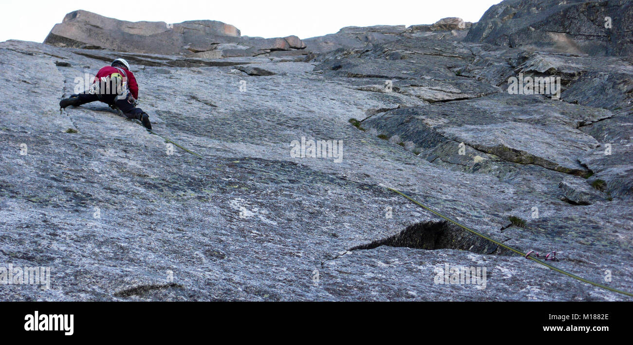 male rock climber on a steep granite route in the mountains near ...