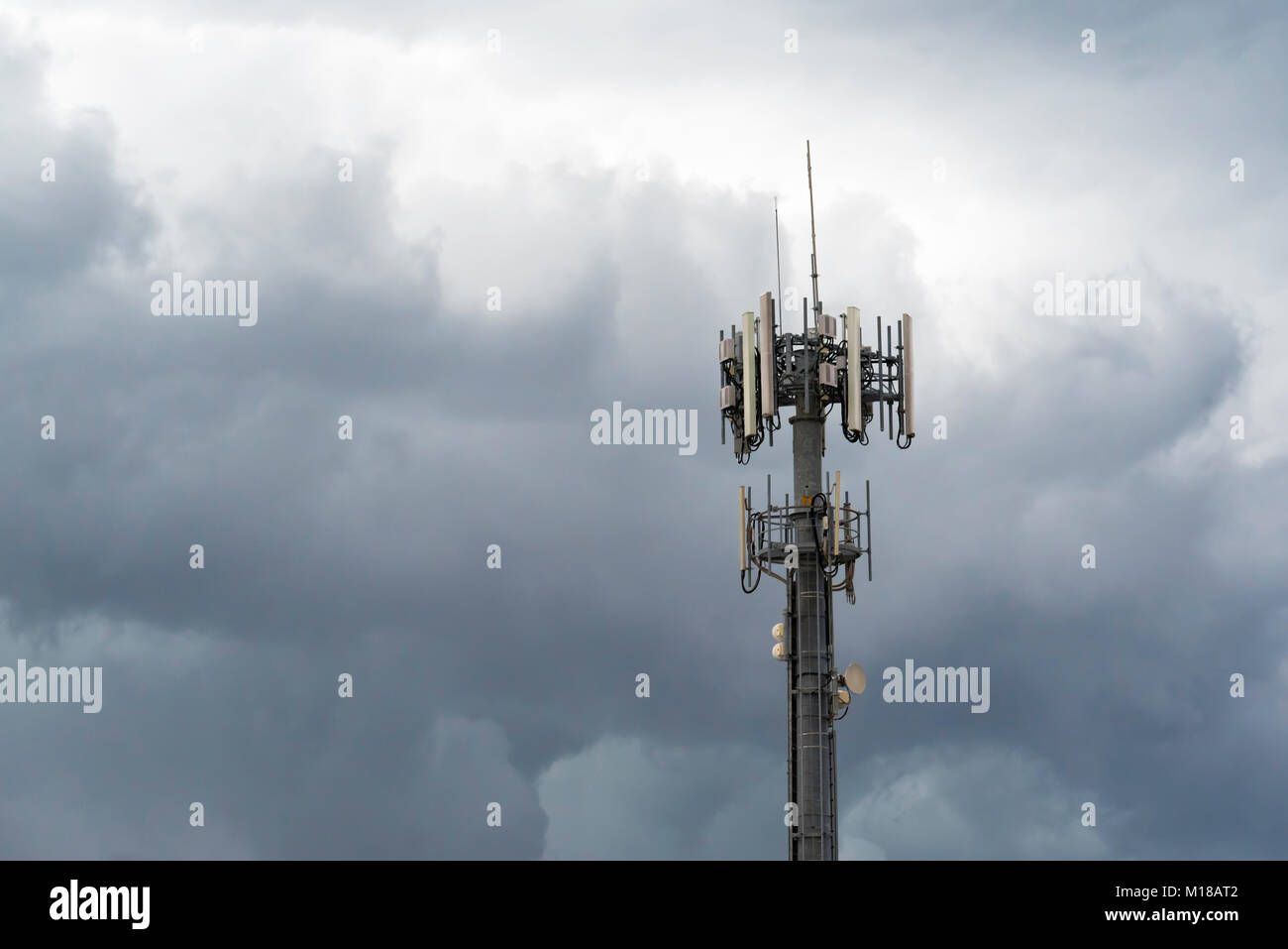 An Australian mobile or cell phone tower with dark grey storm clouds in ...