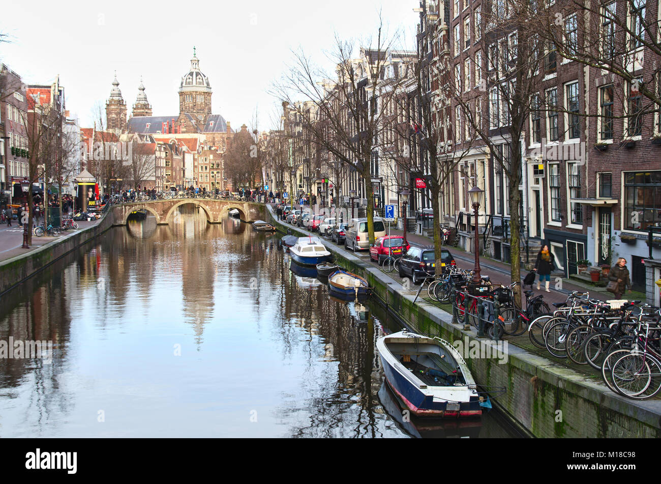 A typical Amsterdam canal scene with boats along the roads and ...