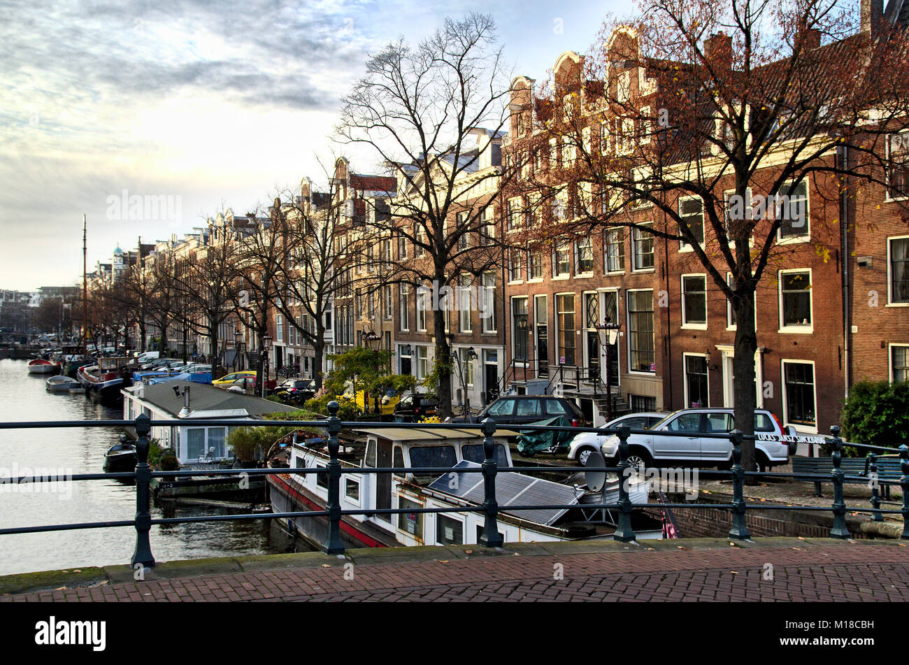 A typical Amsterdam canal scene with boats along the roads and ...