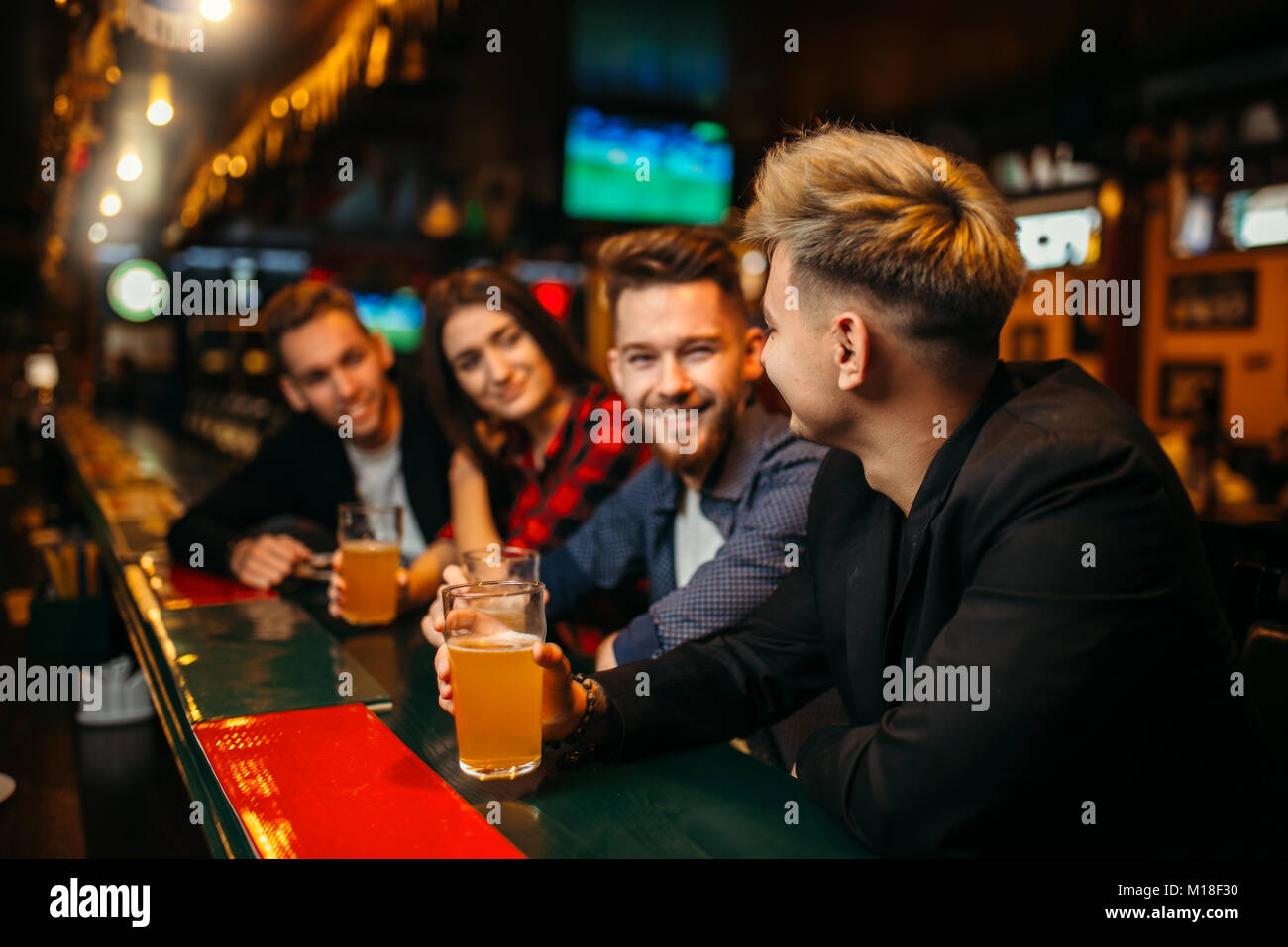 Happy football fans drink beer at the bar counter in a sport pub ...