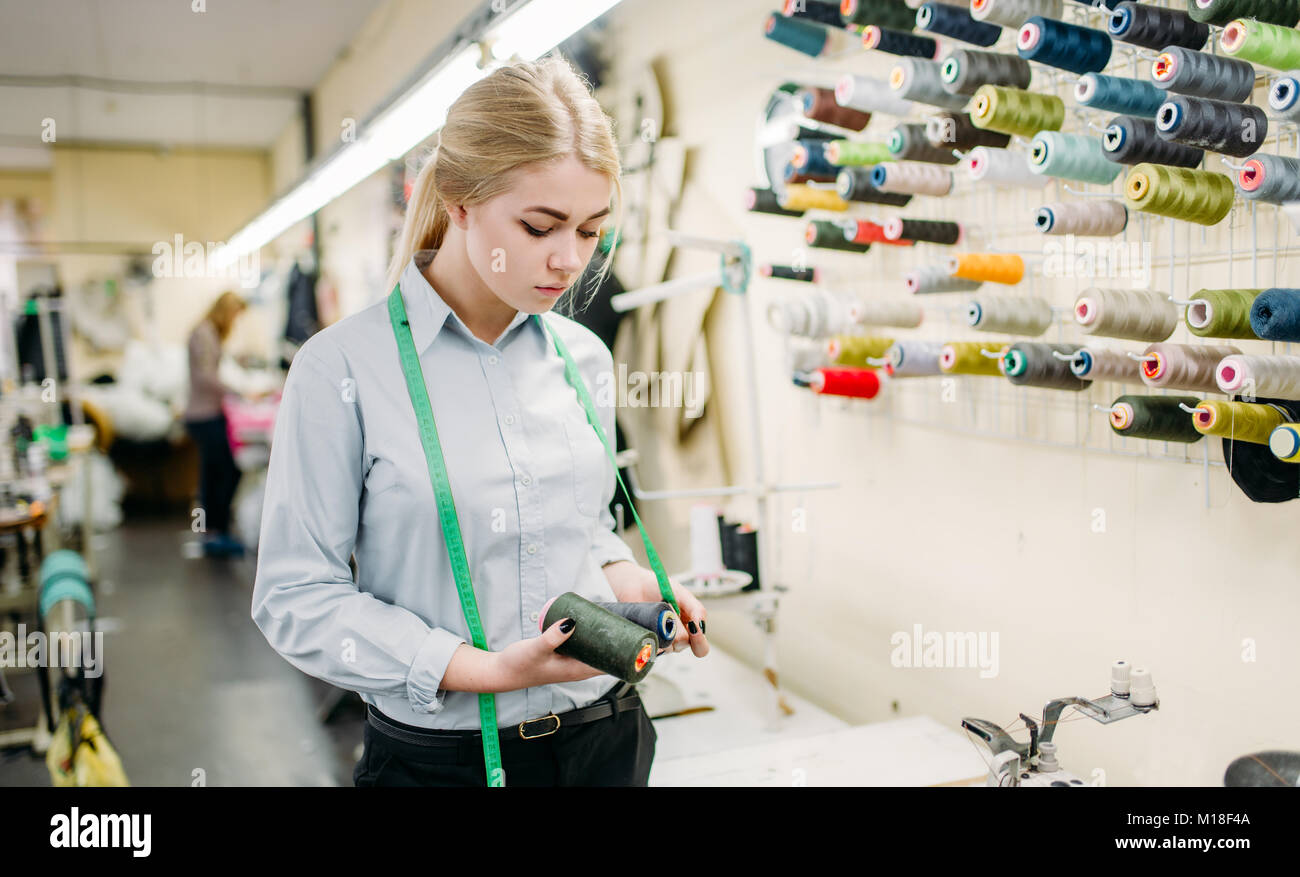 Clothes designer with color threads in hands, manufacture on sewing ...