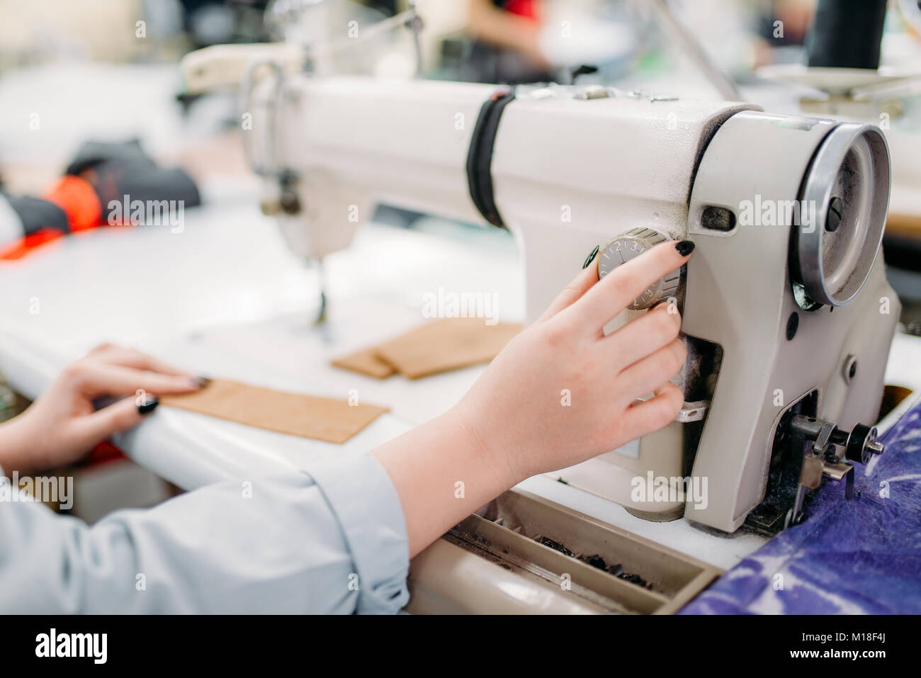 Female dressmaker hands sews fabrics on a sewing machine. Tailoring or ...