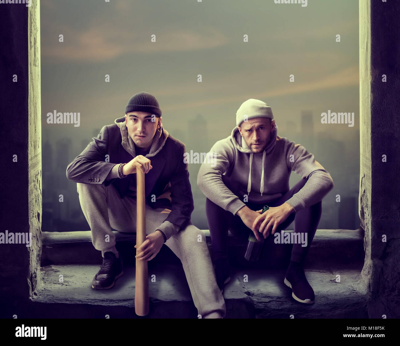Two male robbers are squatting in front of the window. Street gangsters ...