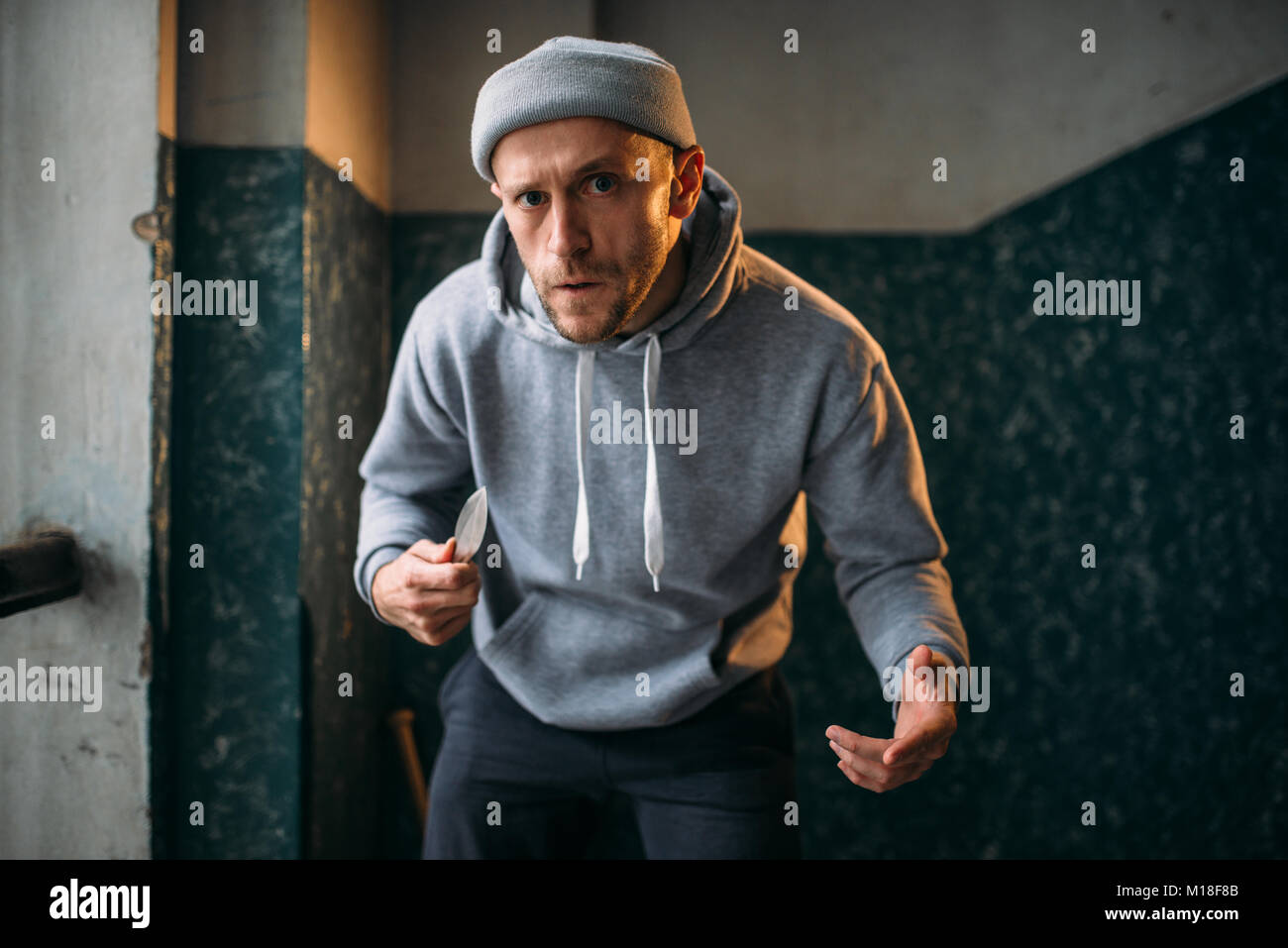 Aggressive male robber with knife strikes fear. Street bandit waiting ...