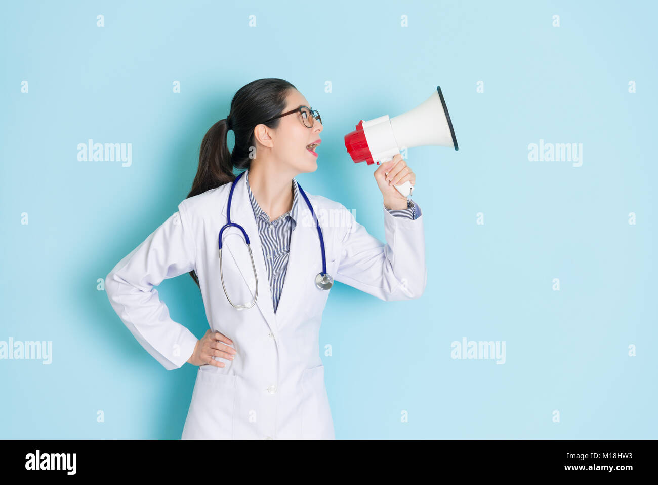 happy beautiful female doctor using loudspeaker face to empty area ...