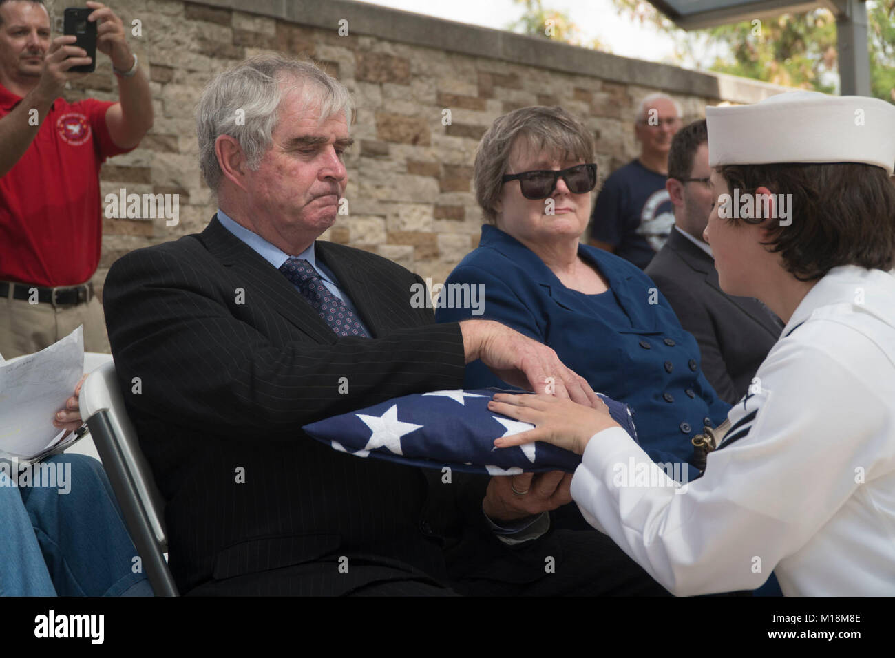 A U.S. Sailor assigned to Navy Region Hawaii presents the American flag ...