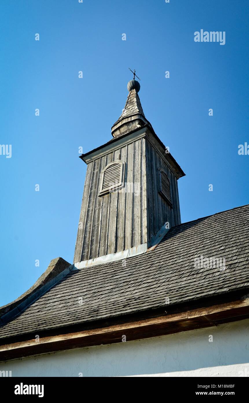 wooden tower of old church with cross and window on blue sky and sunny ...