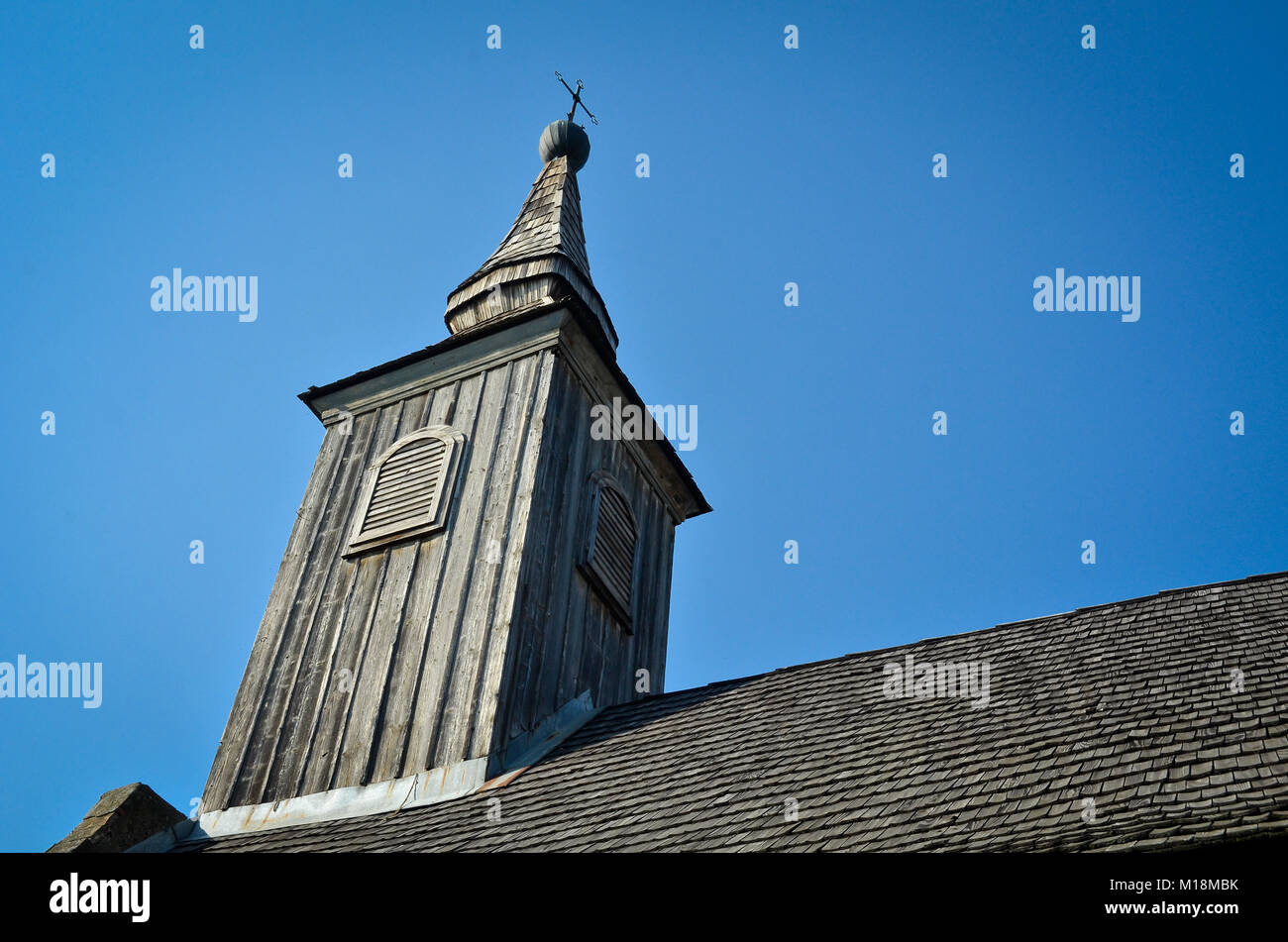 wooden tower of old church with cross and window on blue sky and sunny ...