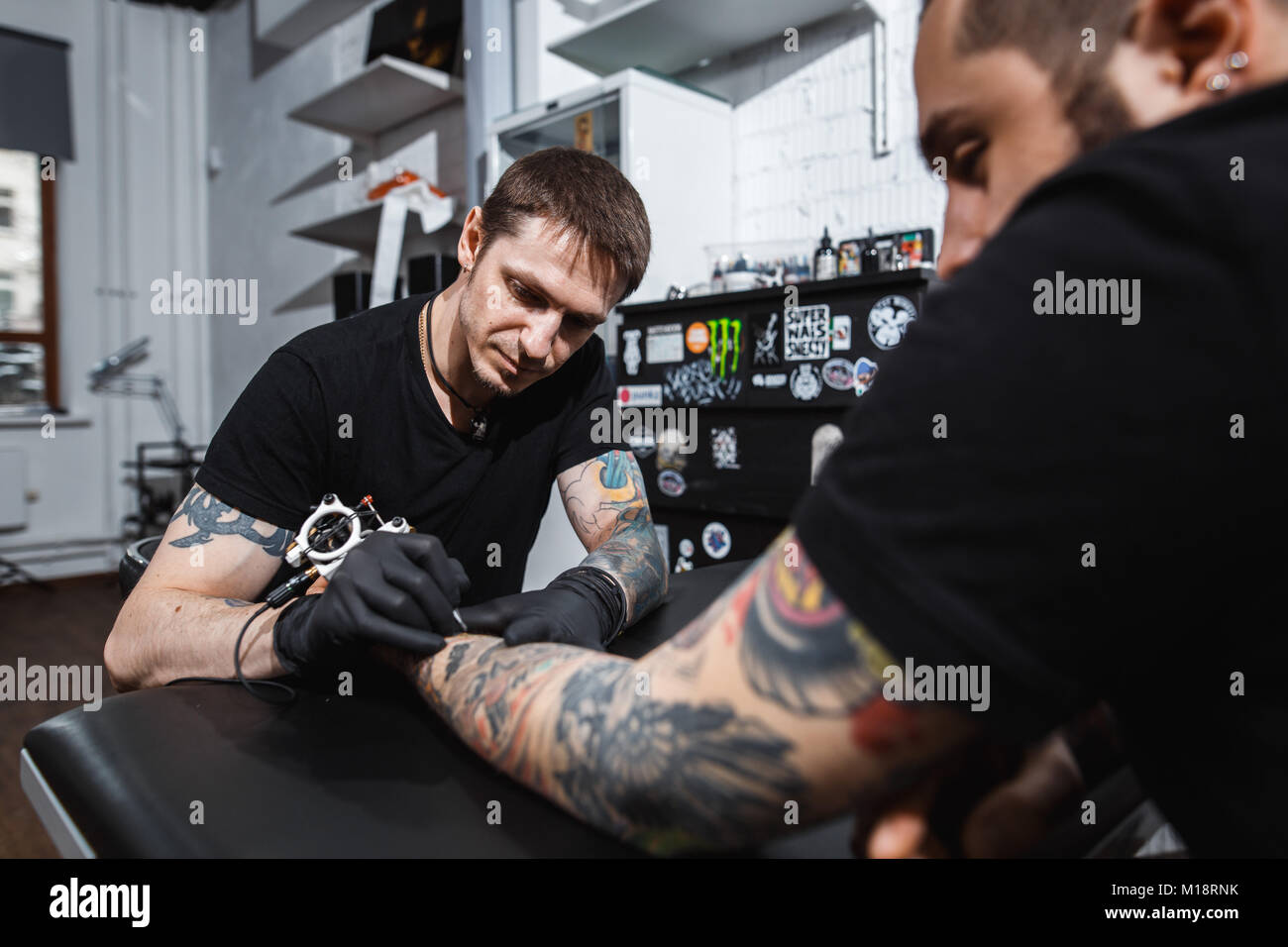 master tattooist makes a tattoo on the skin of the client with special ...