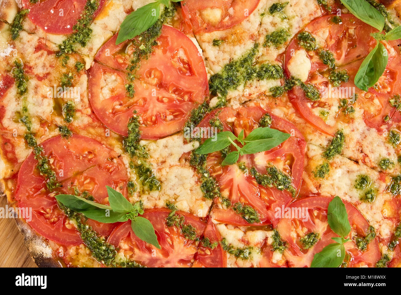 Close up sliced pizza with tomatoes, cheese and greens Stock Photo - Alamy