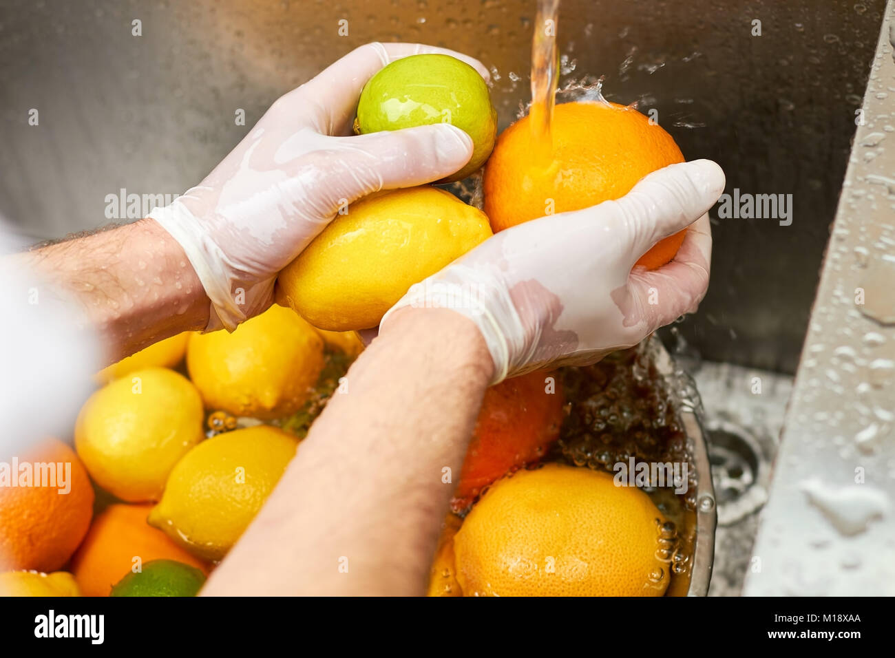 Wet orange, lemon and lime in chef hands rinsing by tap water Stock ...
