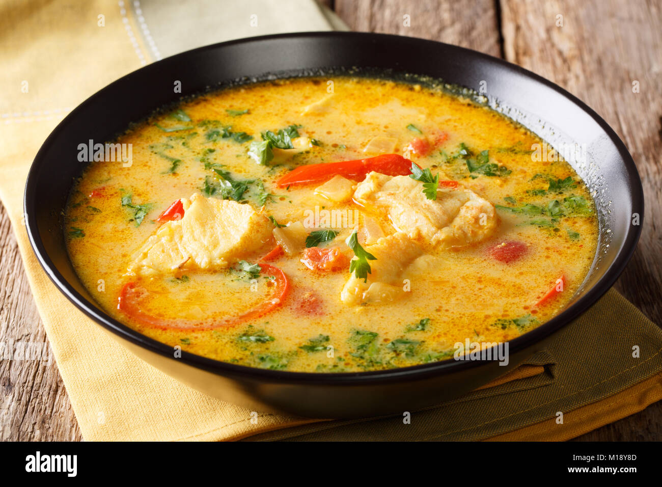 Moqueca stew fish with bell peppers in spicy coconut sauce close-up on ...