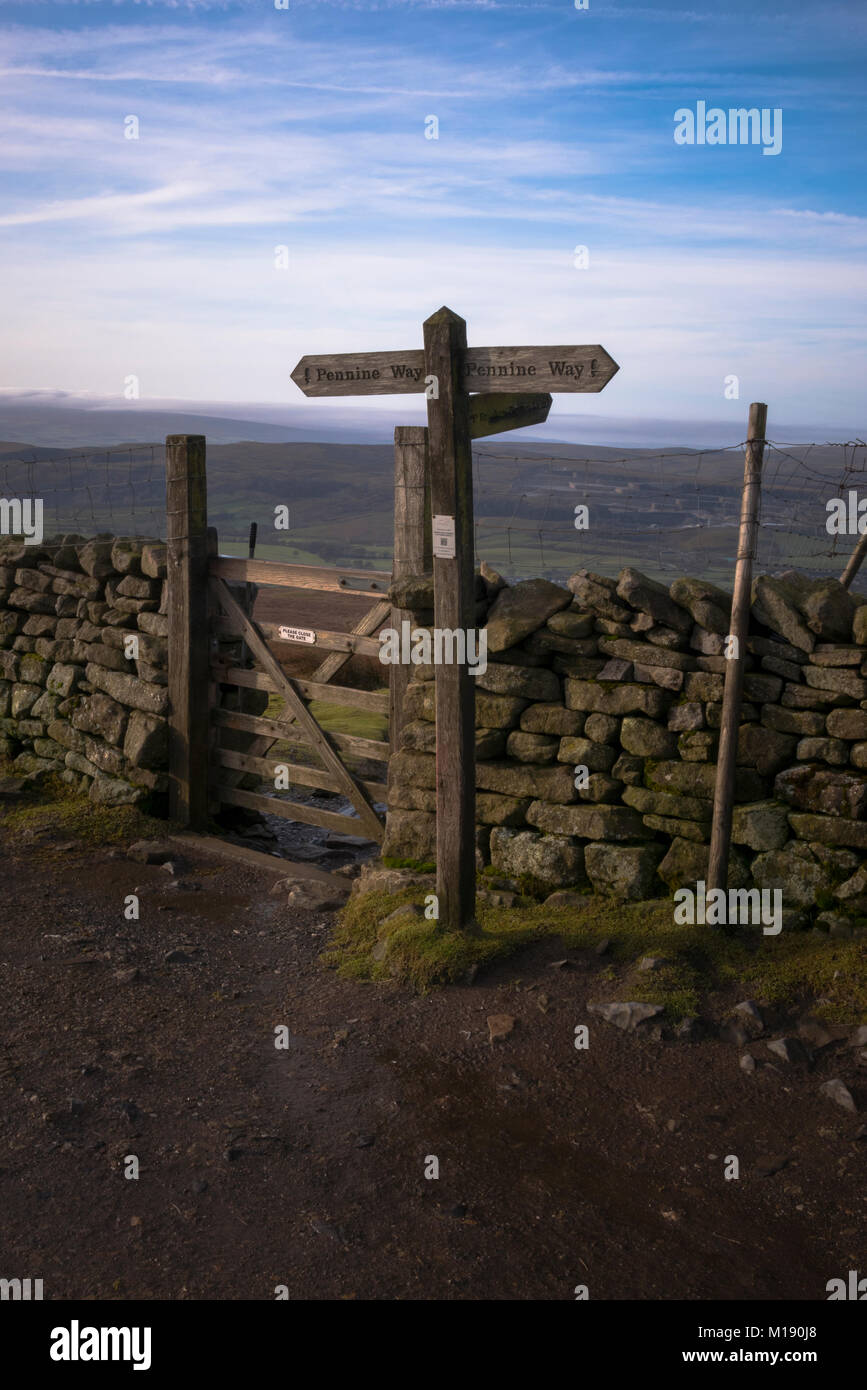 Signpost marking the Pennine Way path route leading up the steep end of ...