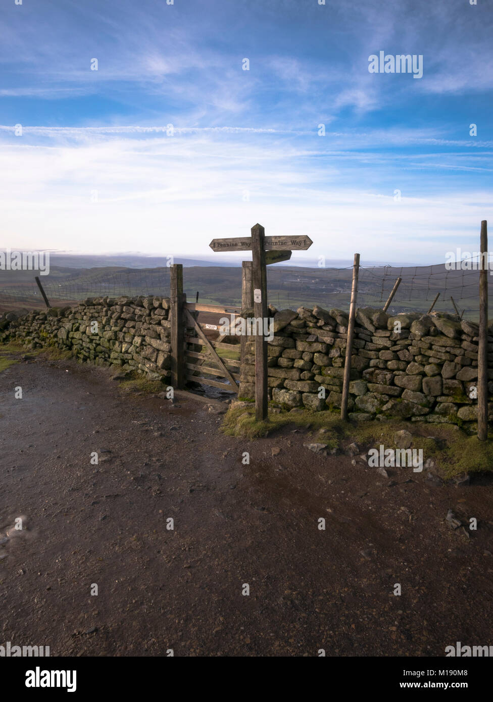 Signpost marking the Pennine Way path route leading up the steep end of ...