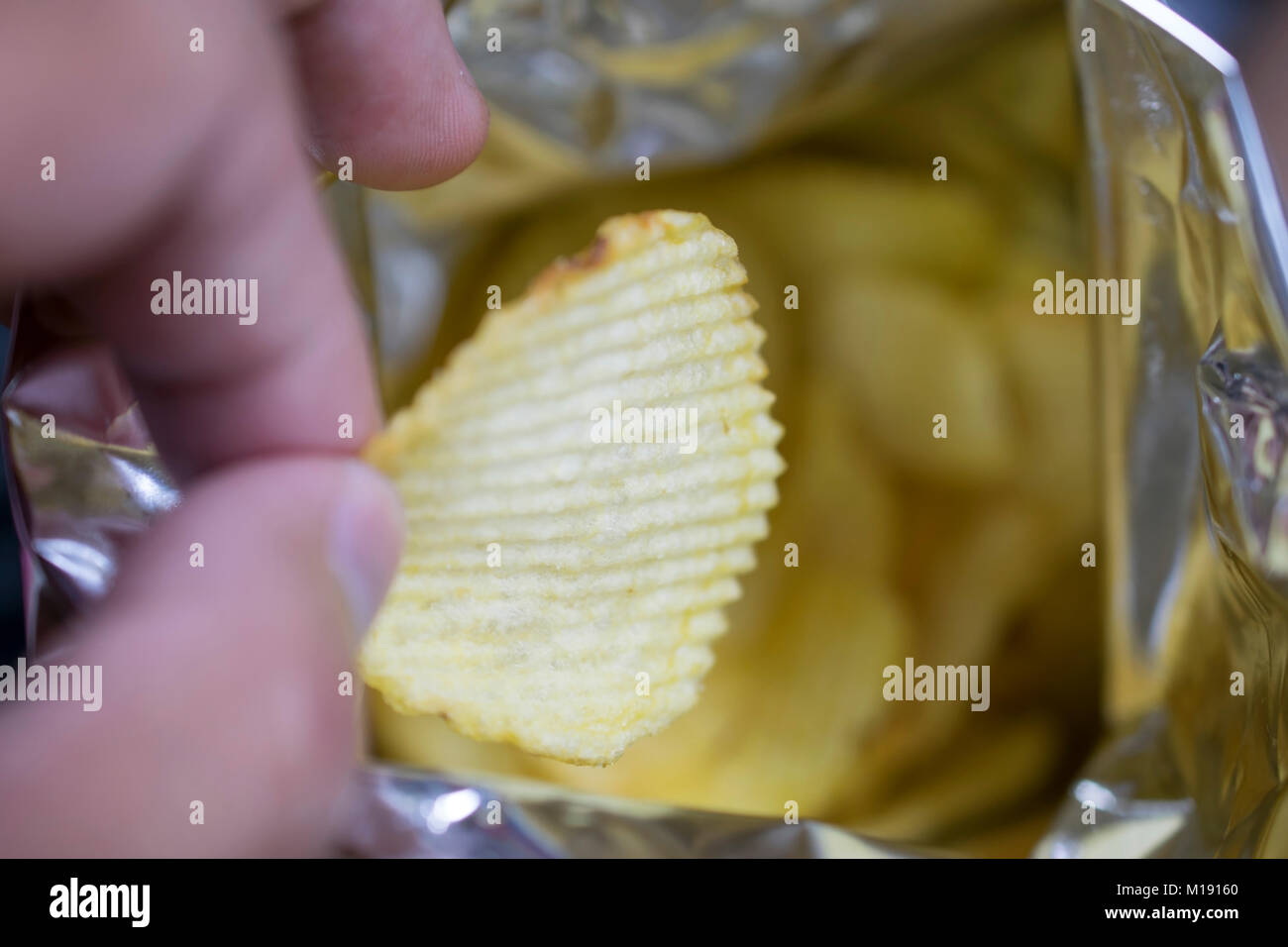 hand holding Potato chips from snack bag - closeup Stock Photo - Alamy