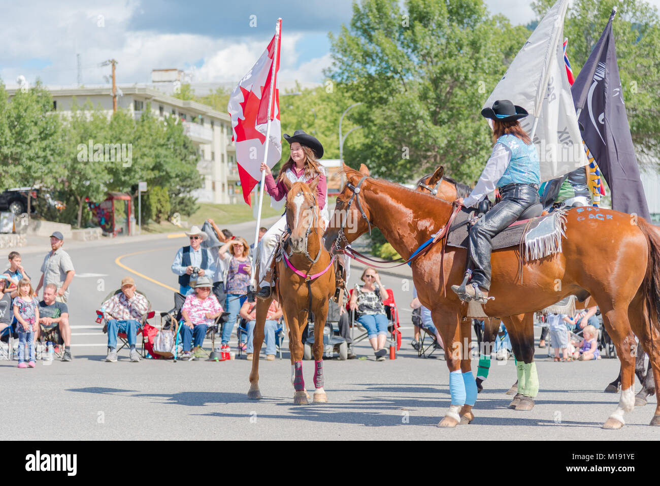 A young girl rides a horse and proudly carries the Canadian flag during ...