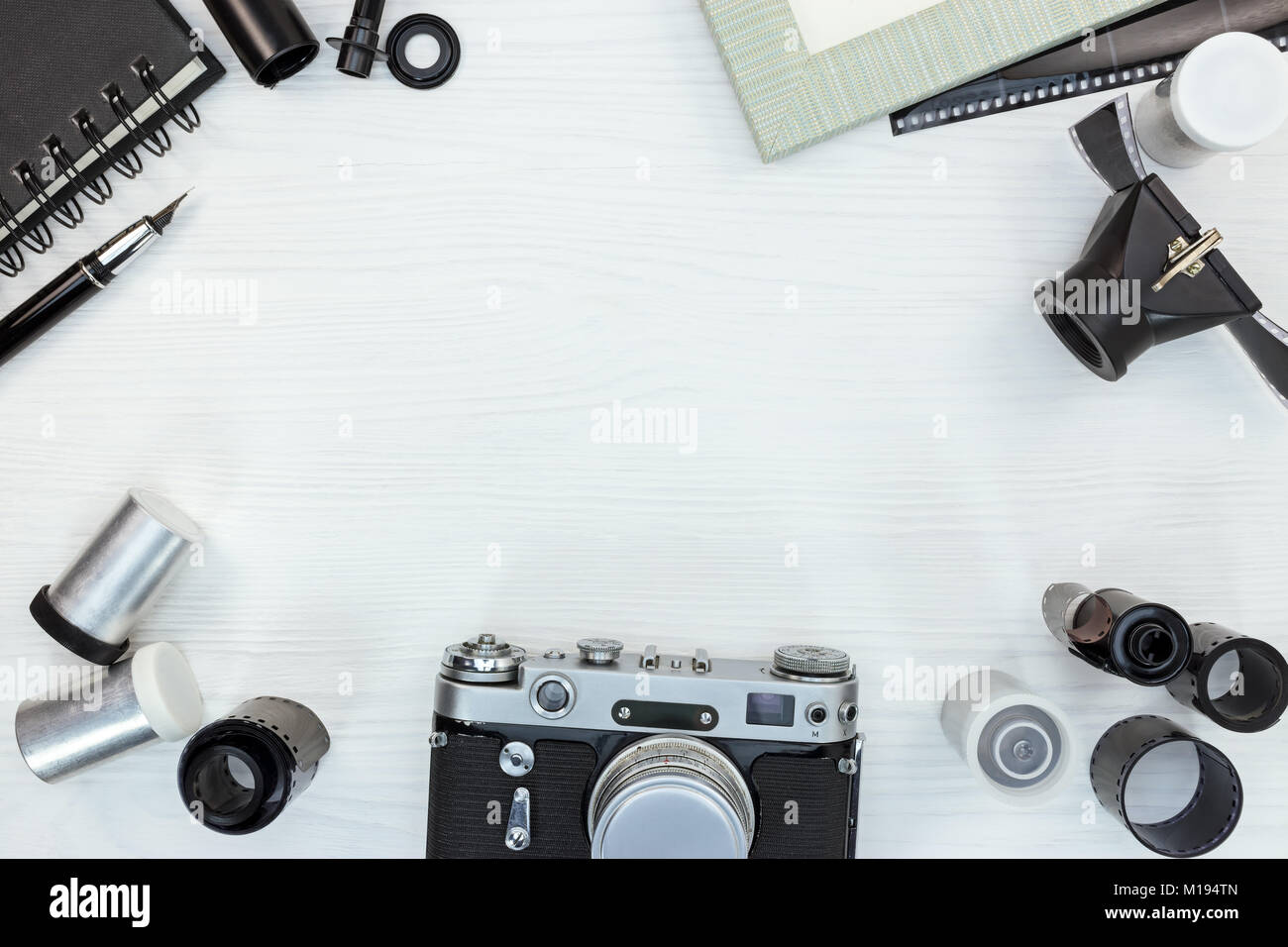 retro camera, film rolls, lens, empty photo frame on white wooden ...