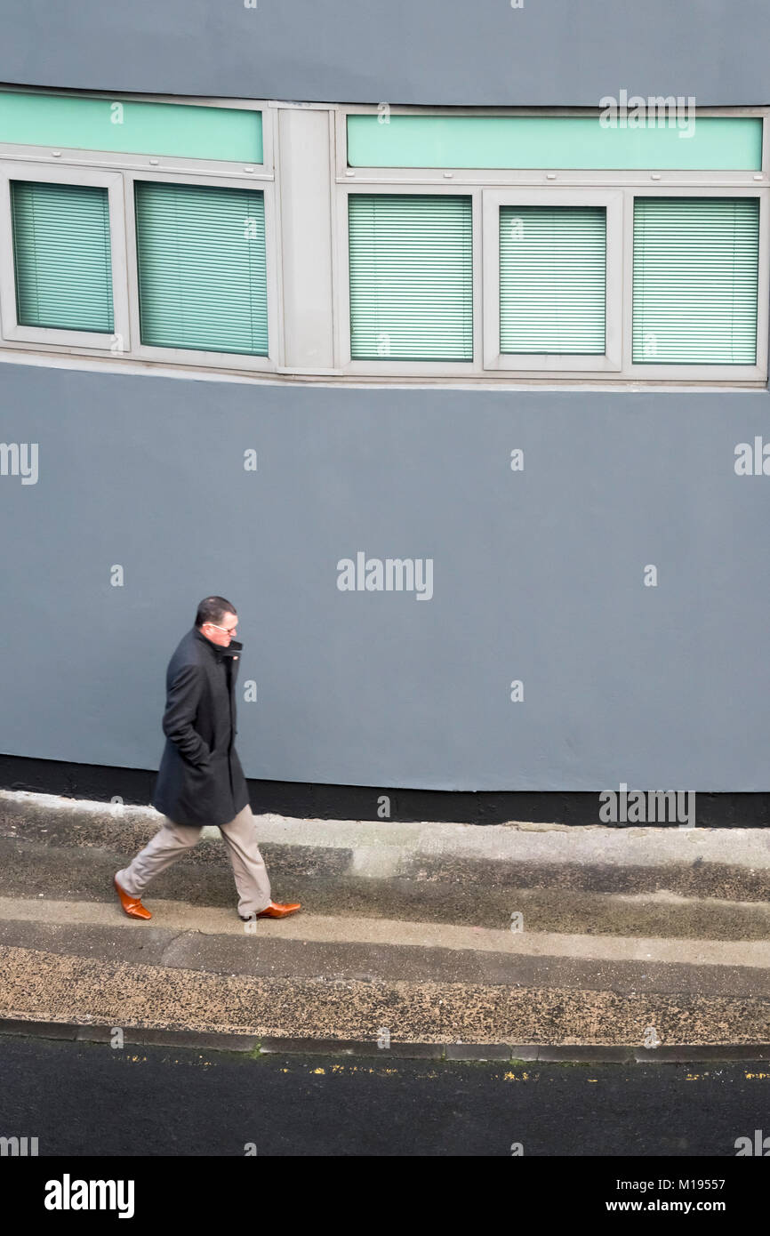 man walking past a grey painted building Stock Photo - Alamy
