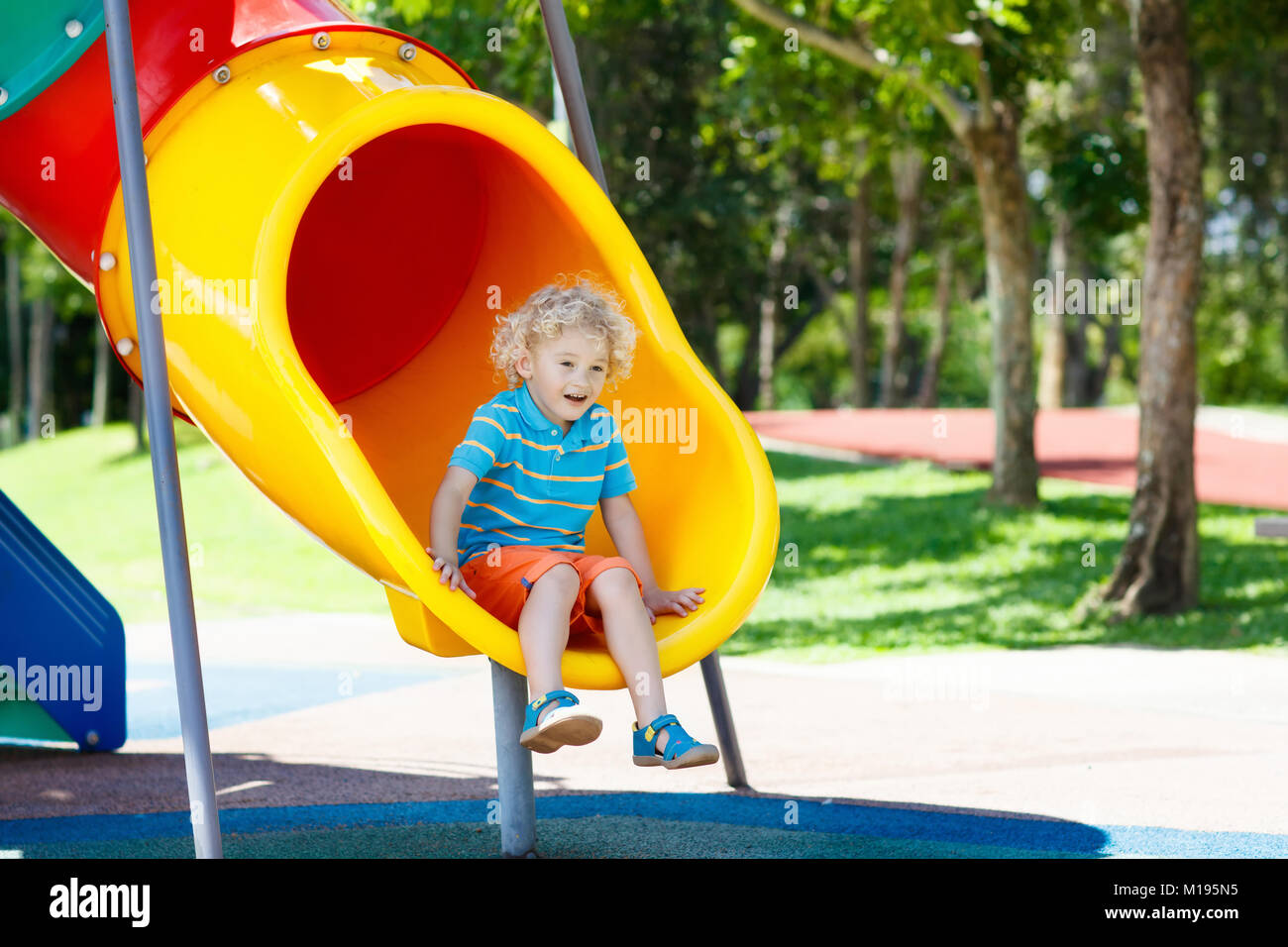 Kids climbing and sliding on outdoor playground. Children play in sunny ...