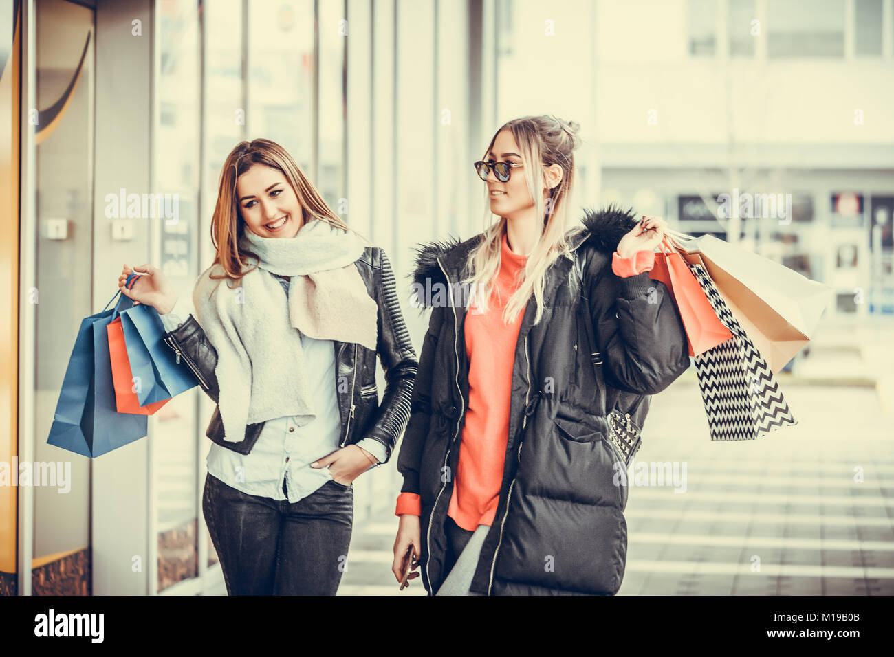 Happy friends shopping. Two beautiful young women enjoying shopping in ...