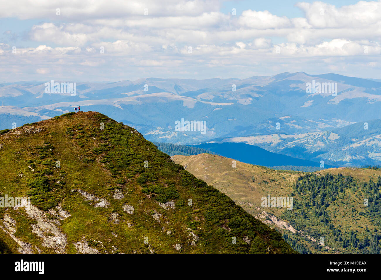 Two hikers standing on a huge mountain cliff. Hiking tourism. Power of ...