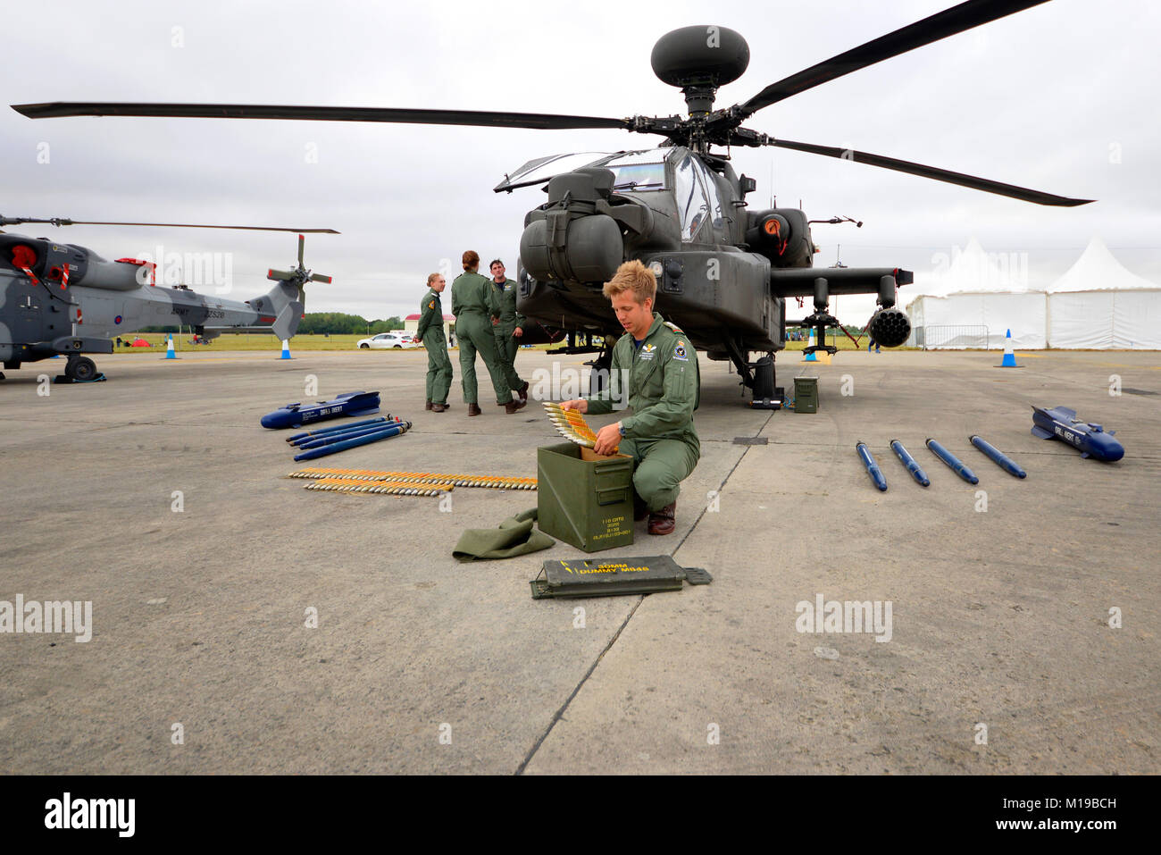 British Army AH-64 Apache gunship with crewman loading gun shells into ...