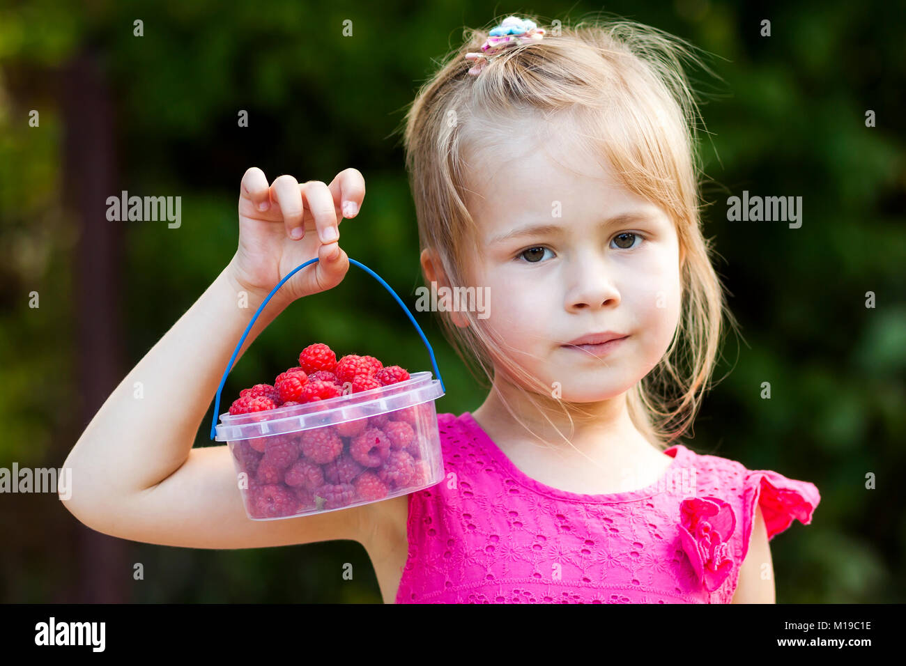 Portrait of a little girl child holdind small basket of ripe ...