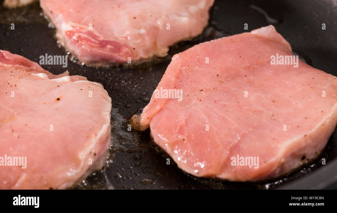 Frying slices of pork muscles meat on pan with oil Stock Photo - Alamy