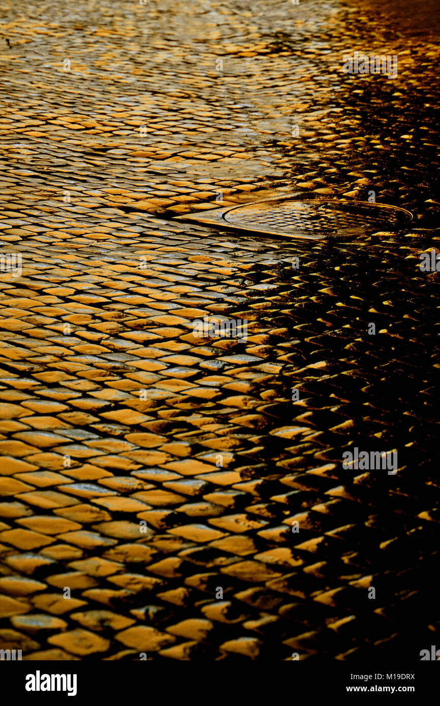Wet cobbled street at night lit by yellow lights Stock Photo - Alamy