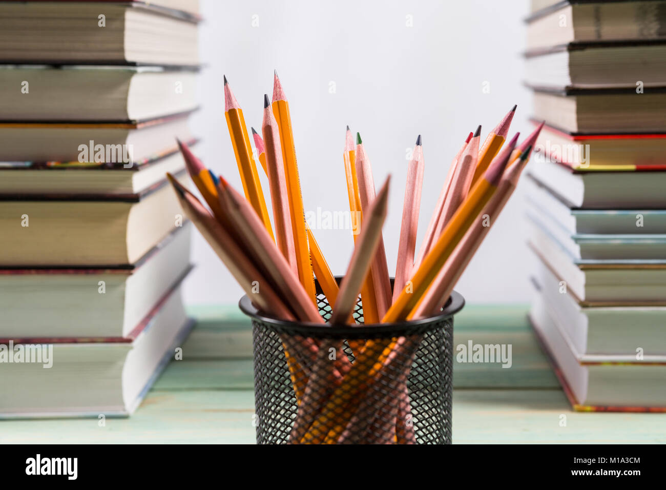 Set of pencils and pile of various books on wooden background. With ...