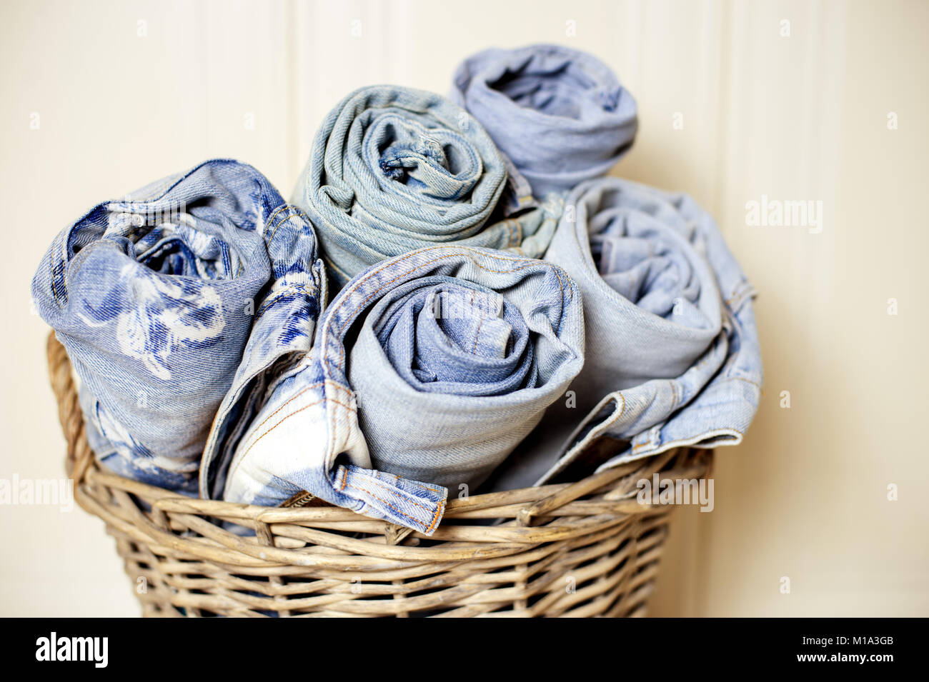 rolled jeans in a laundry basket on floor beige and blue combination ...