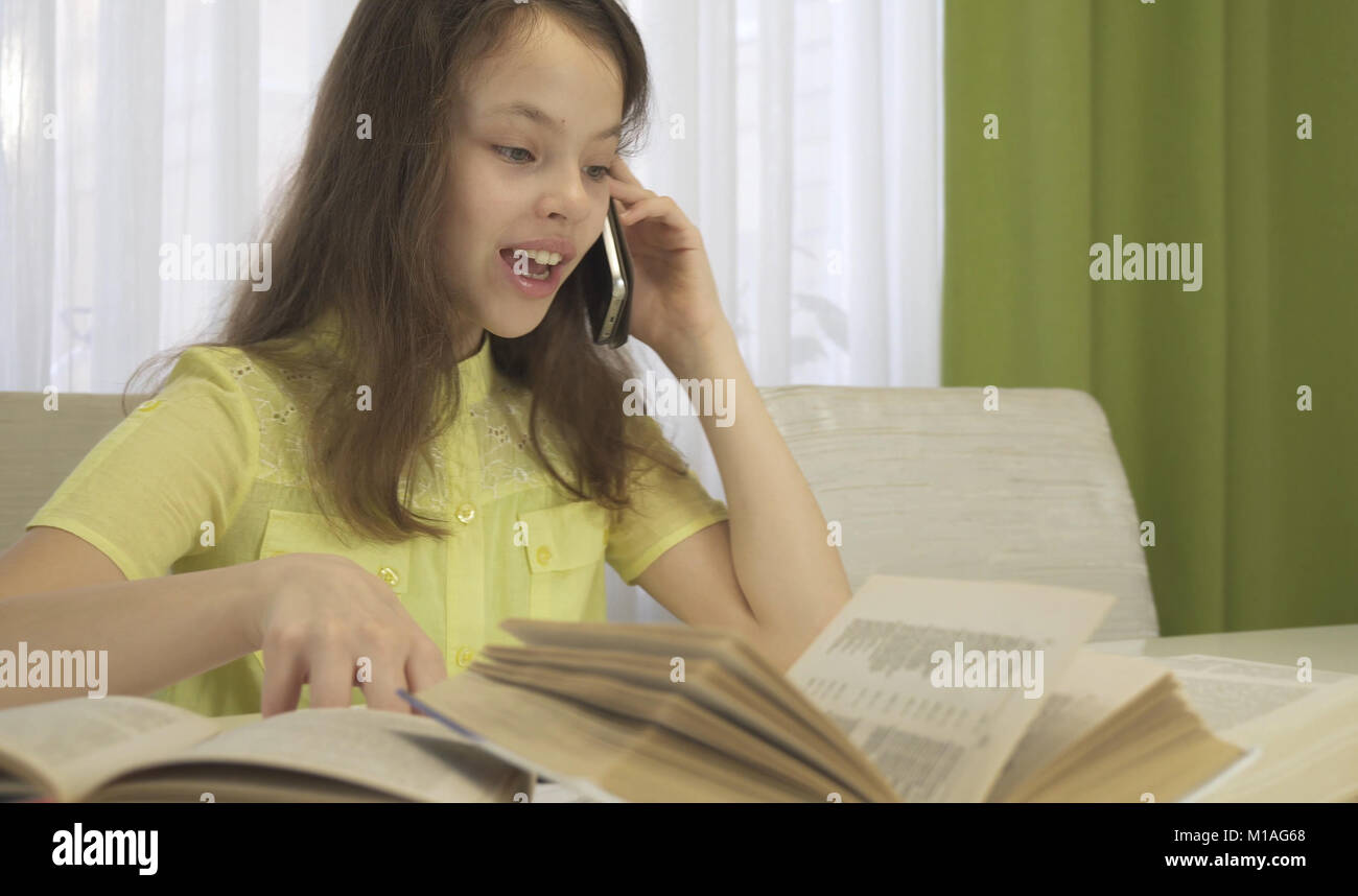 Teenager girl is distracted by telephone conversation while doing her ...