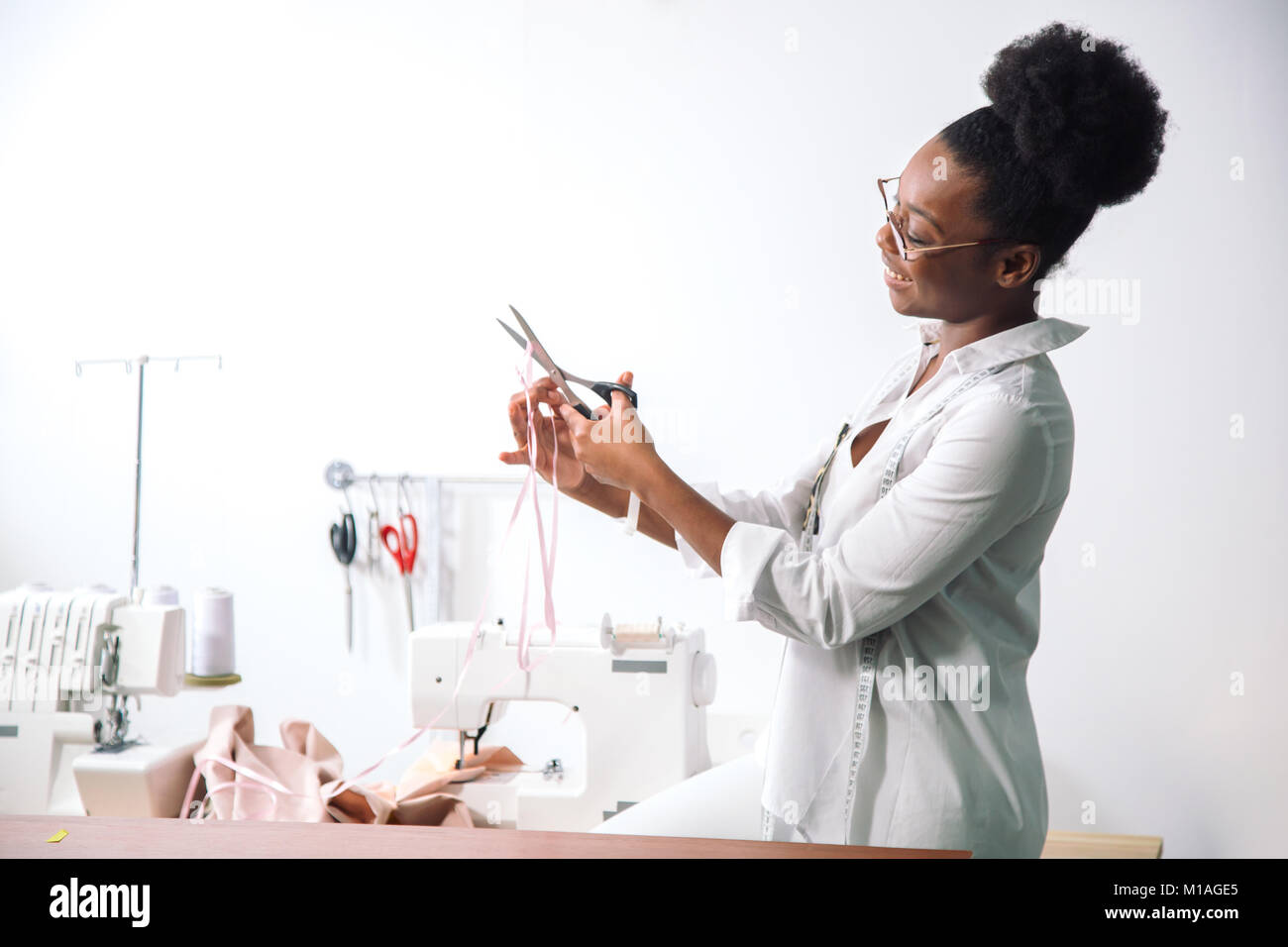 Dressmaker cuts dress detail or thread Stock Photo - Alamy