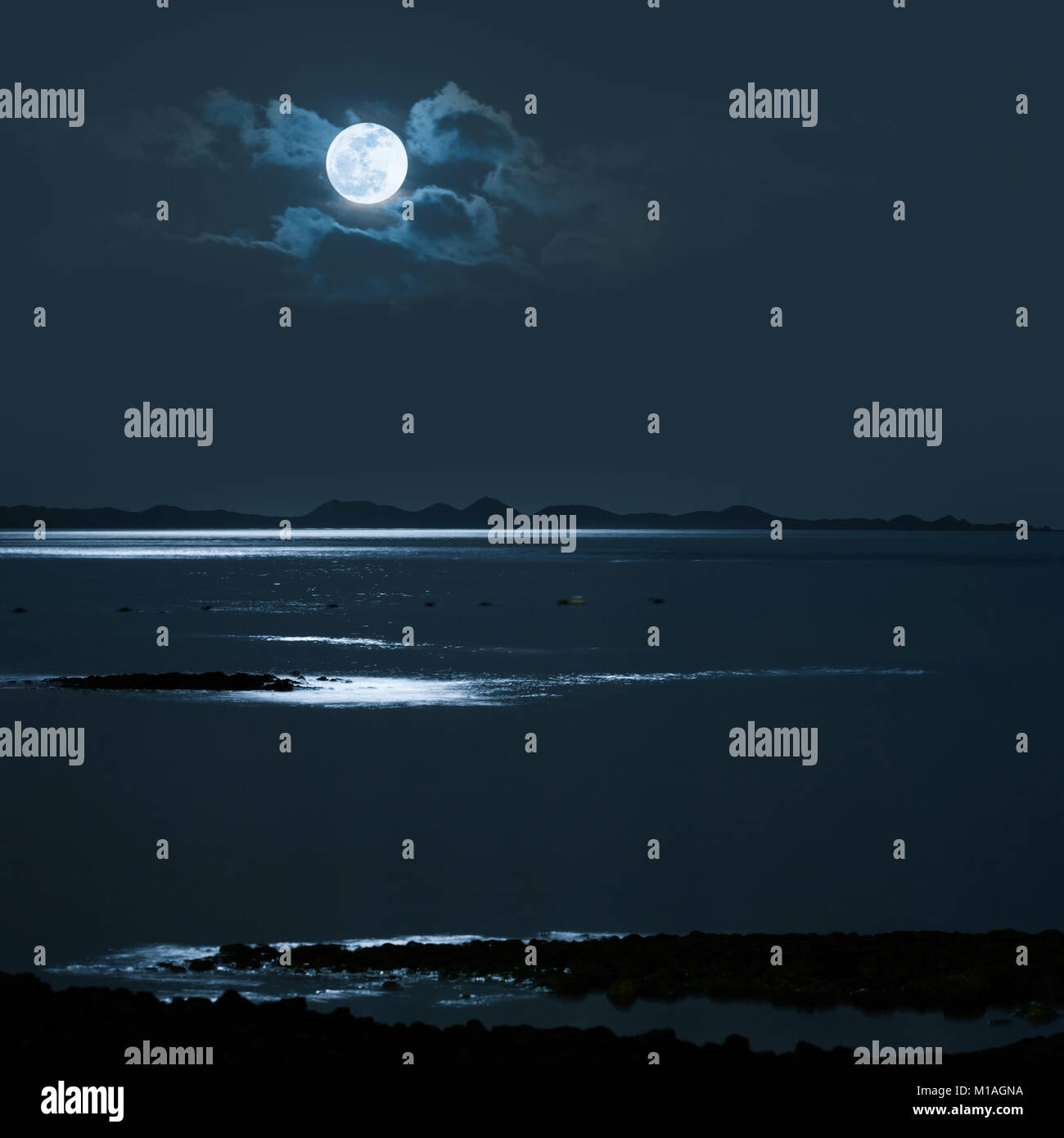 Full Moon over calm sea with a distanc shore Stock Photo - Alamy