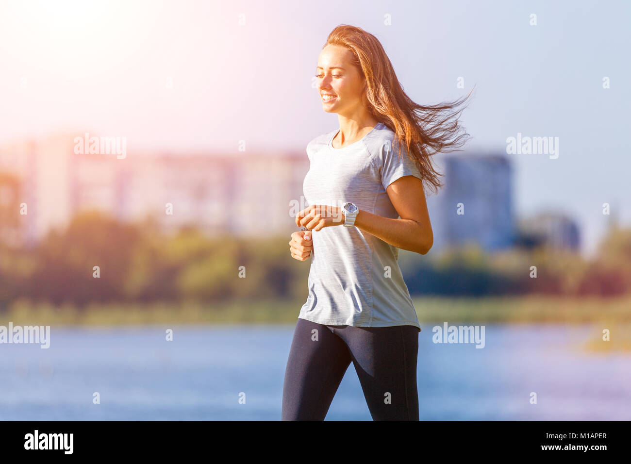 Young smiling sporty woman running in park in the morning. Fitness girl ...