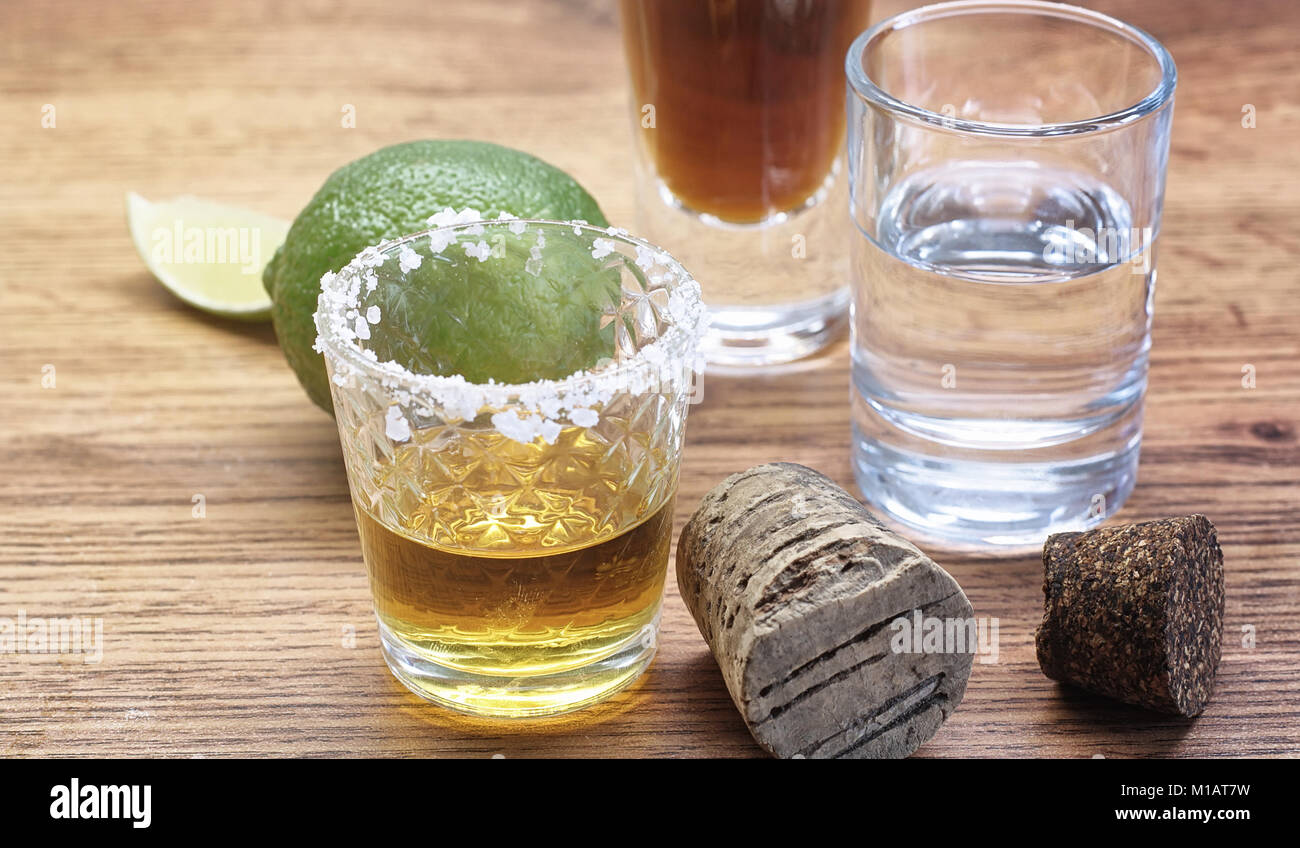 Alcoholic strong drinks on the background and pieces of lime with salt ...