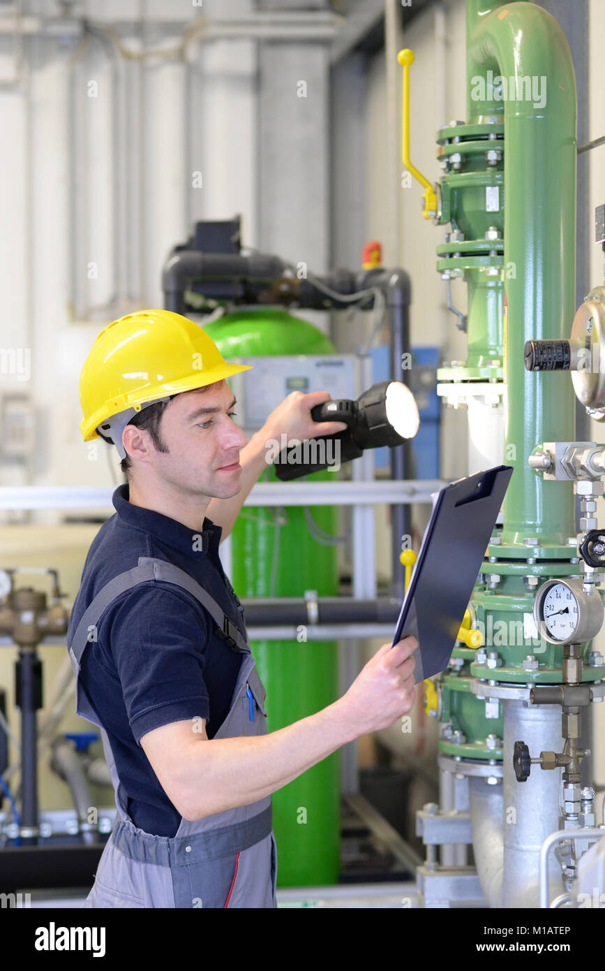 Industrial worker inspects and repairs a heating system in a factory ...