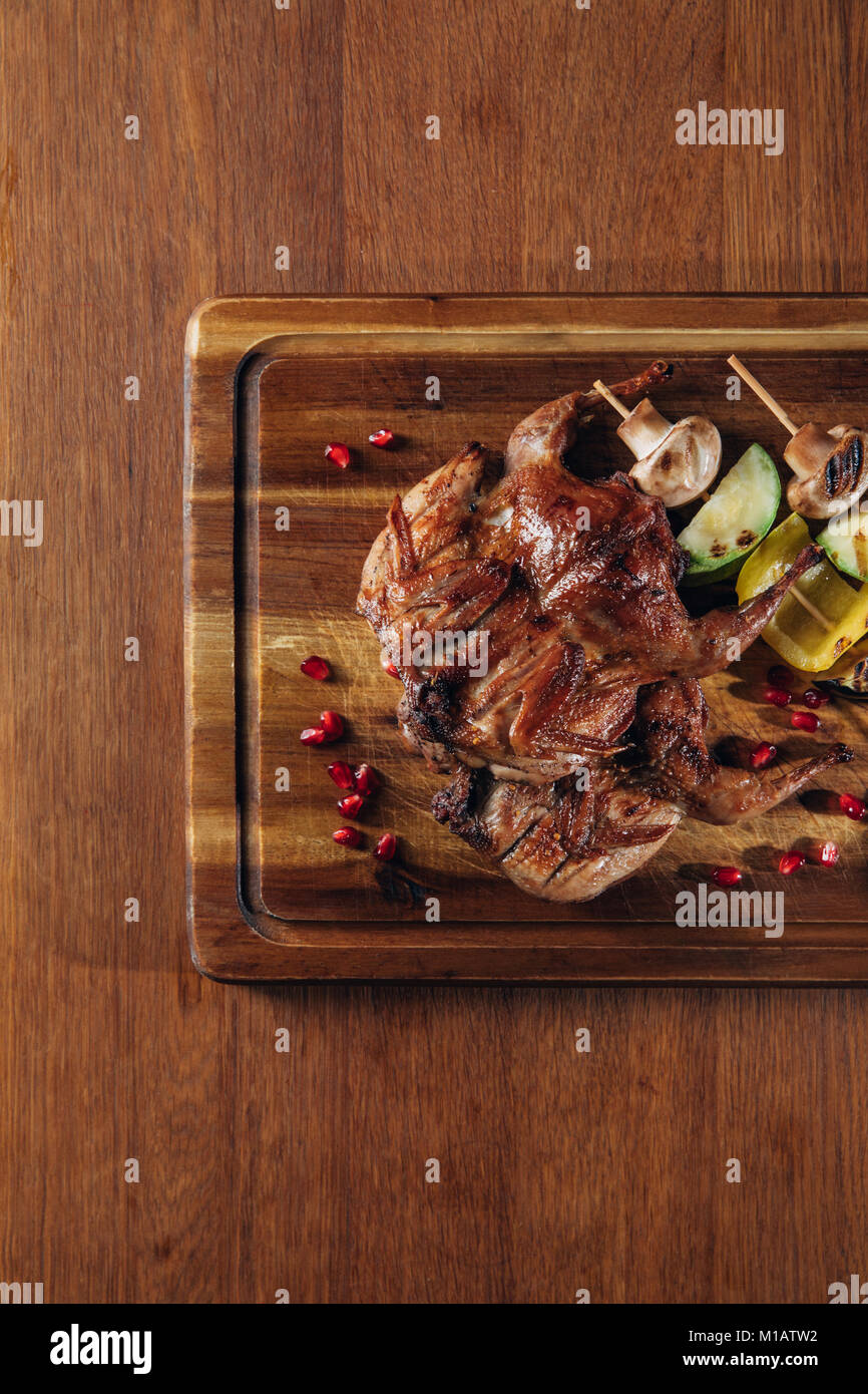top view of delicious roasted quail with vegetables served on wooden ...