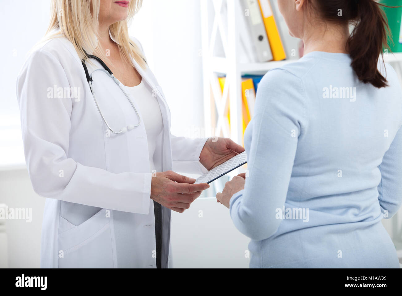 Female doctor holding application form while consulting patient at ...