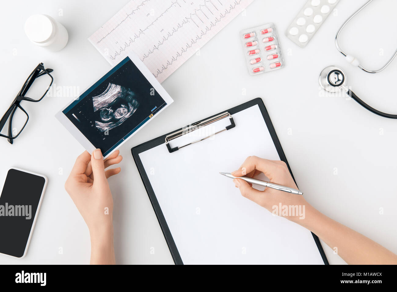 top view of hand with pen over paper on folder and photo with internal ...